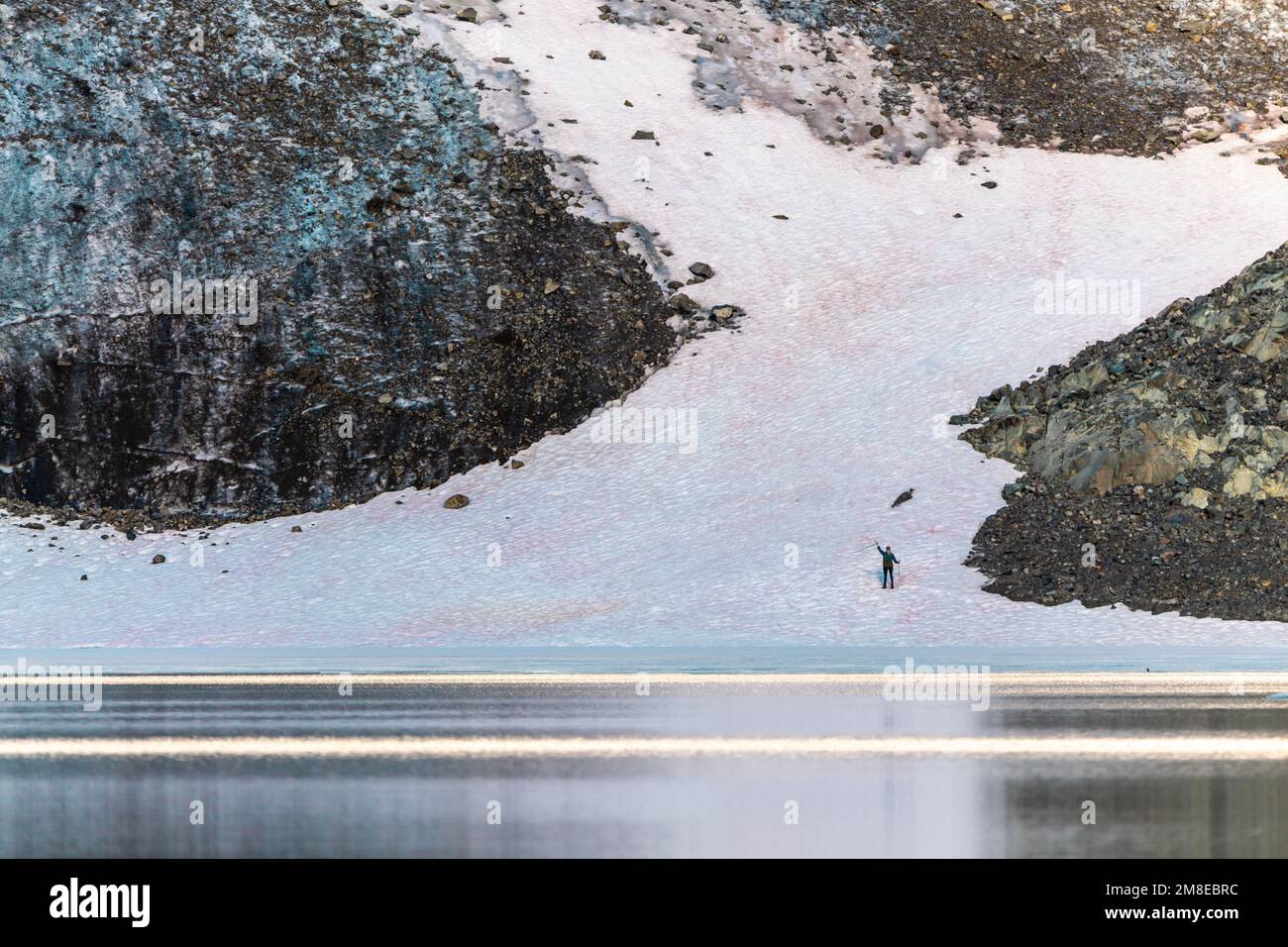 Person hiking in far distance during summer time beside a glacial lake ...