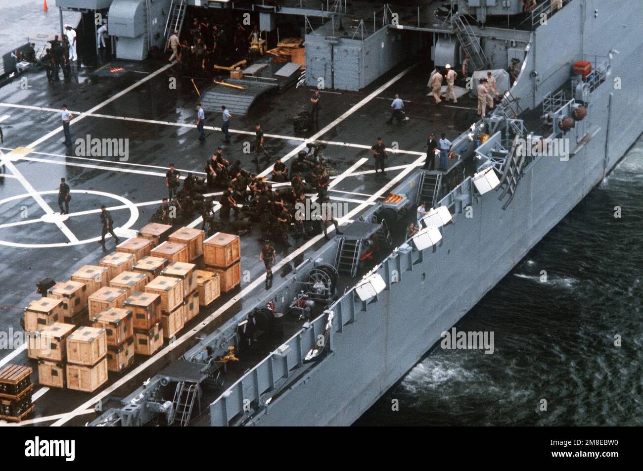 Marines wait with their gear on the flight deck of the amphibious ...