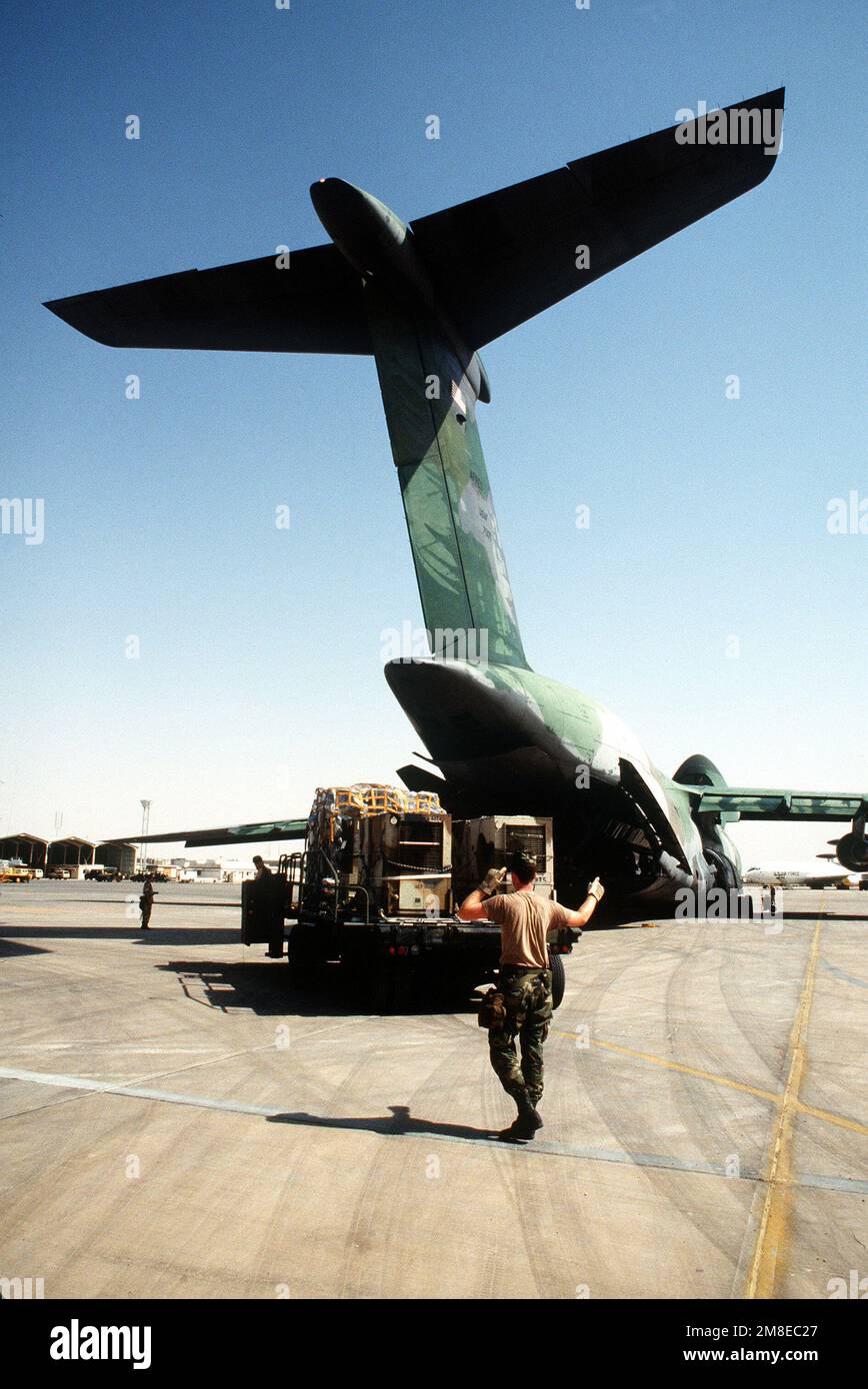 A ground guide directs the driver of a K-loader as he backs away from a ...