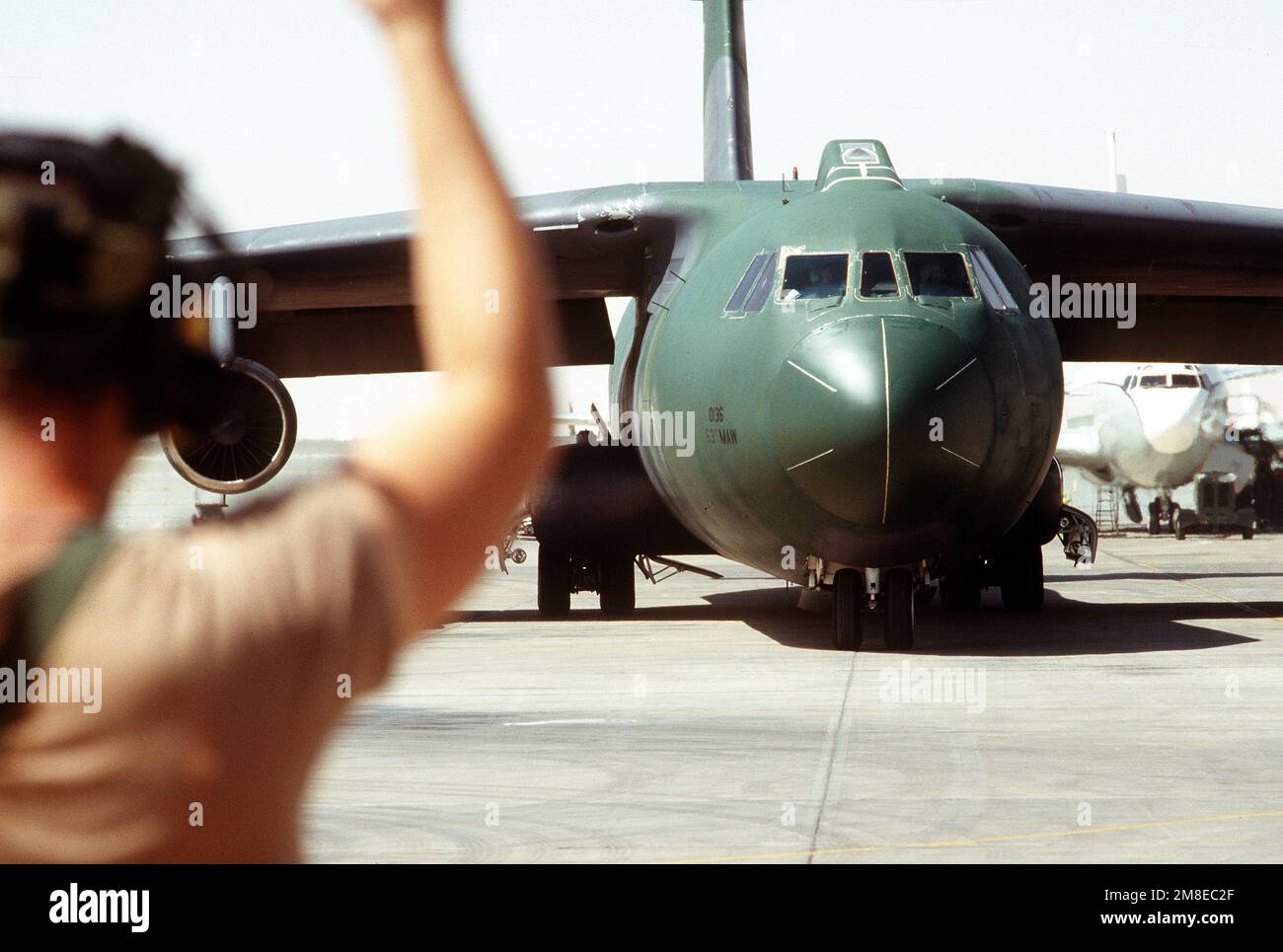 A ground crew member signals to the pilot of a 63rd Military Airlift ...