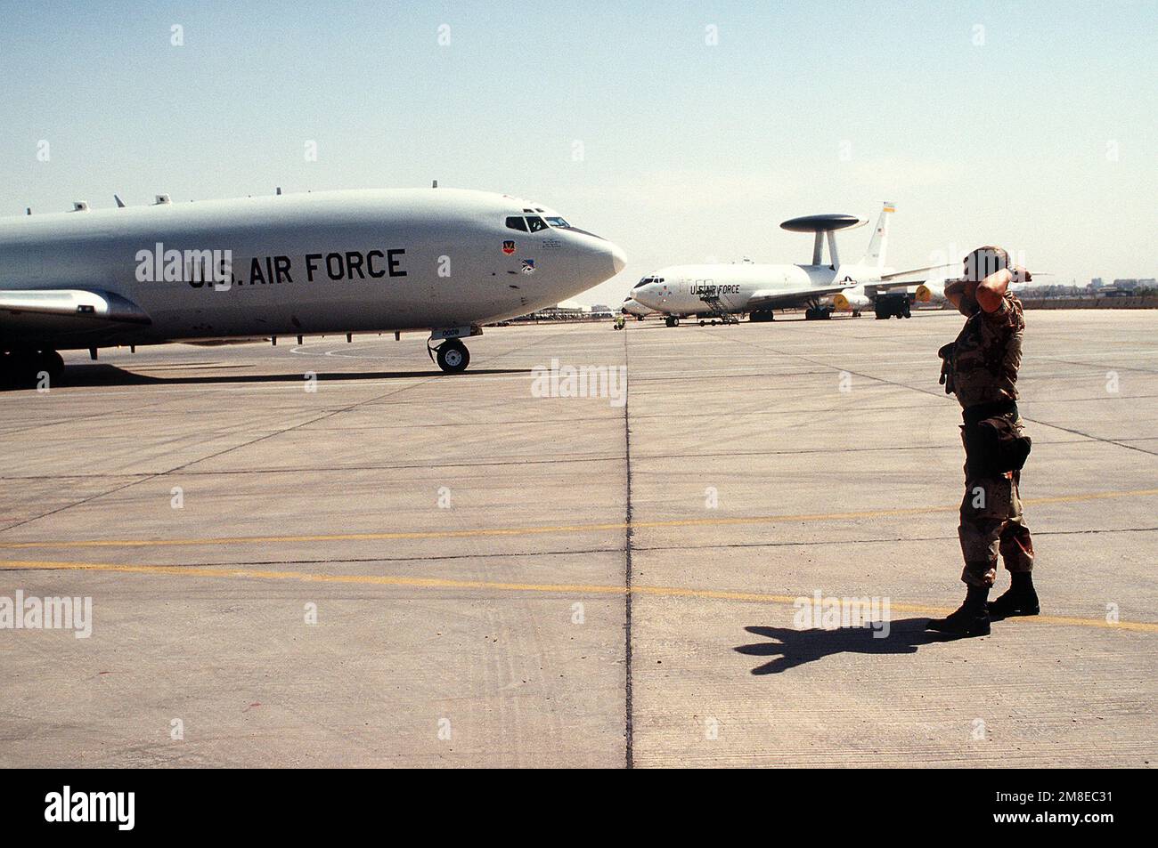 A ground marshal guides an E-3B Sentry aircraft across the apron during ...