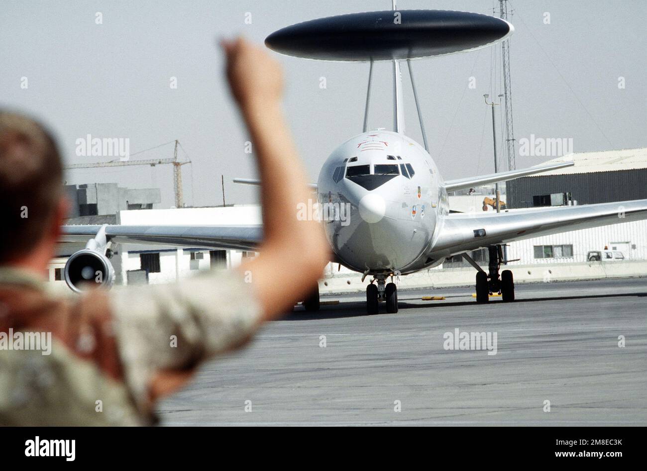 A ground crew member signals to the pilot of an E-3A Sentry aircraft as ...