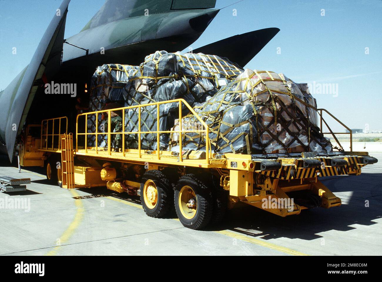 U.S. military personnel load supplies from a K-loader onto a C-141B ...