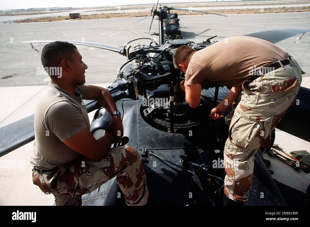 Two mechanics perform maintenance on the main rotor of a UH-60 Black ...