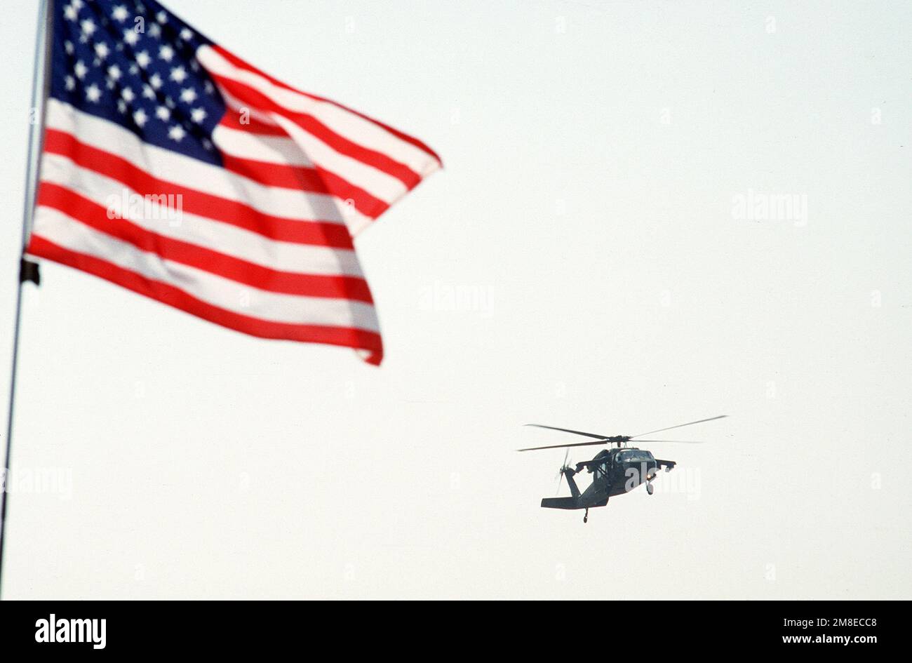 A UH-60 Blackhawk helicopter approaches an American flag flying at a ...