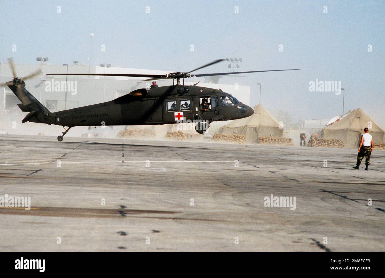 A ground guide watches as a UH-60 Black Hawk (Blackhawk) helicopter ...