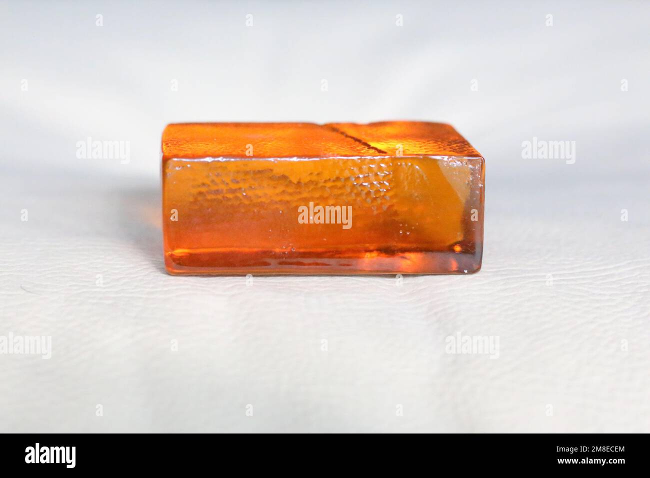 Honey-colored resin violin in a rectangular shape on a white background ...