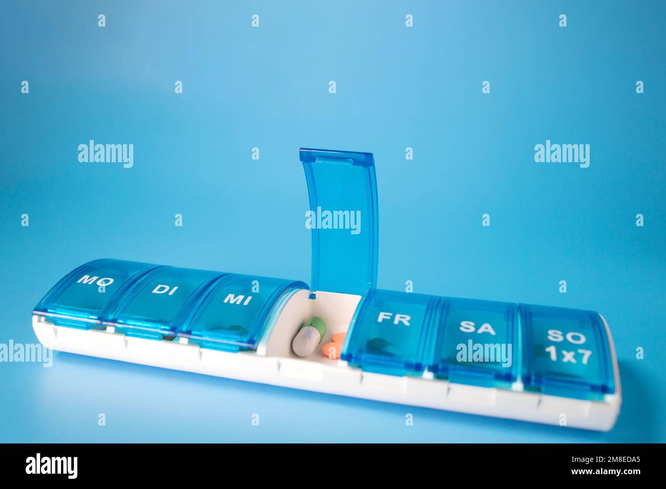 Plastic container with various pills on a blue background. Planning the ...