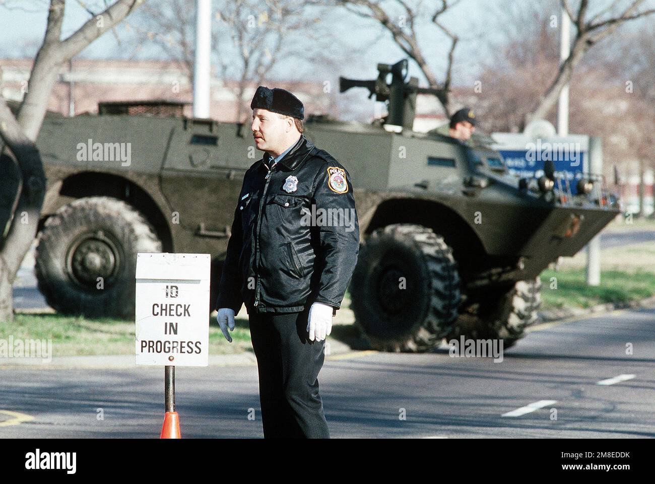 A policeman checks a visitor's identification as a V-100 Commando ...