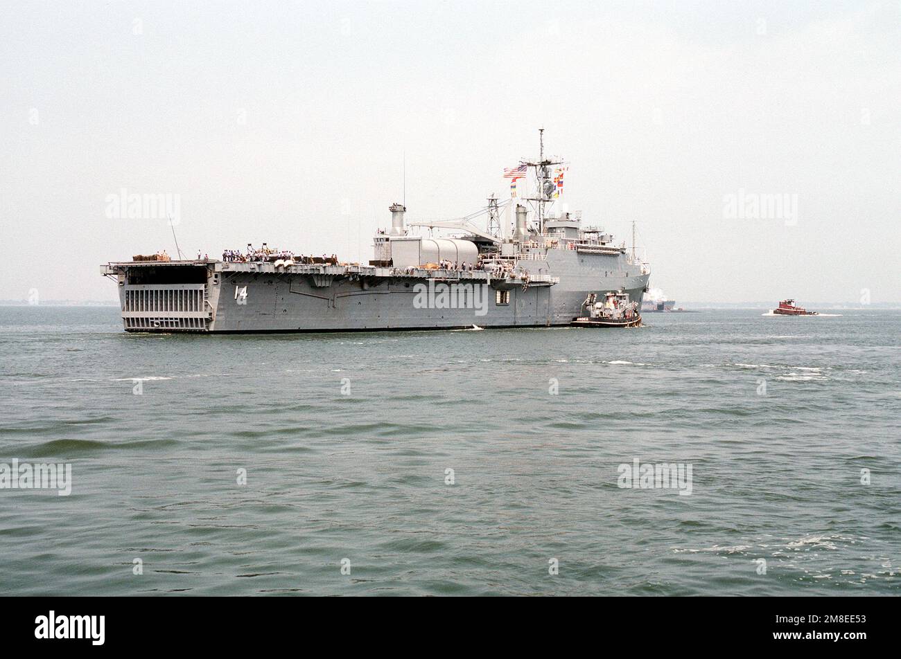 The large harbor tug ANOKA (YTB-810) maneuvers the amphibious transport ...