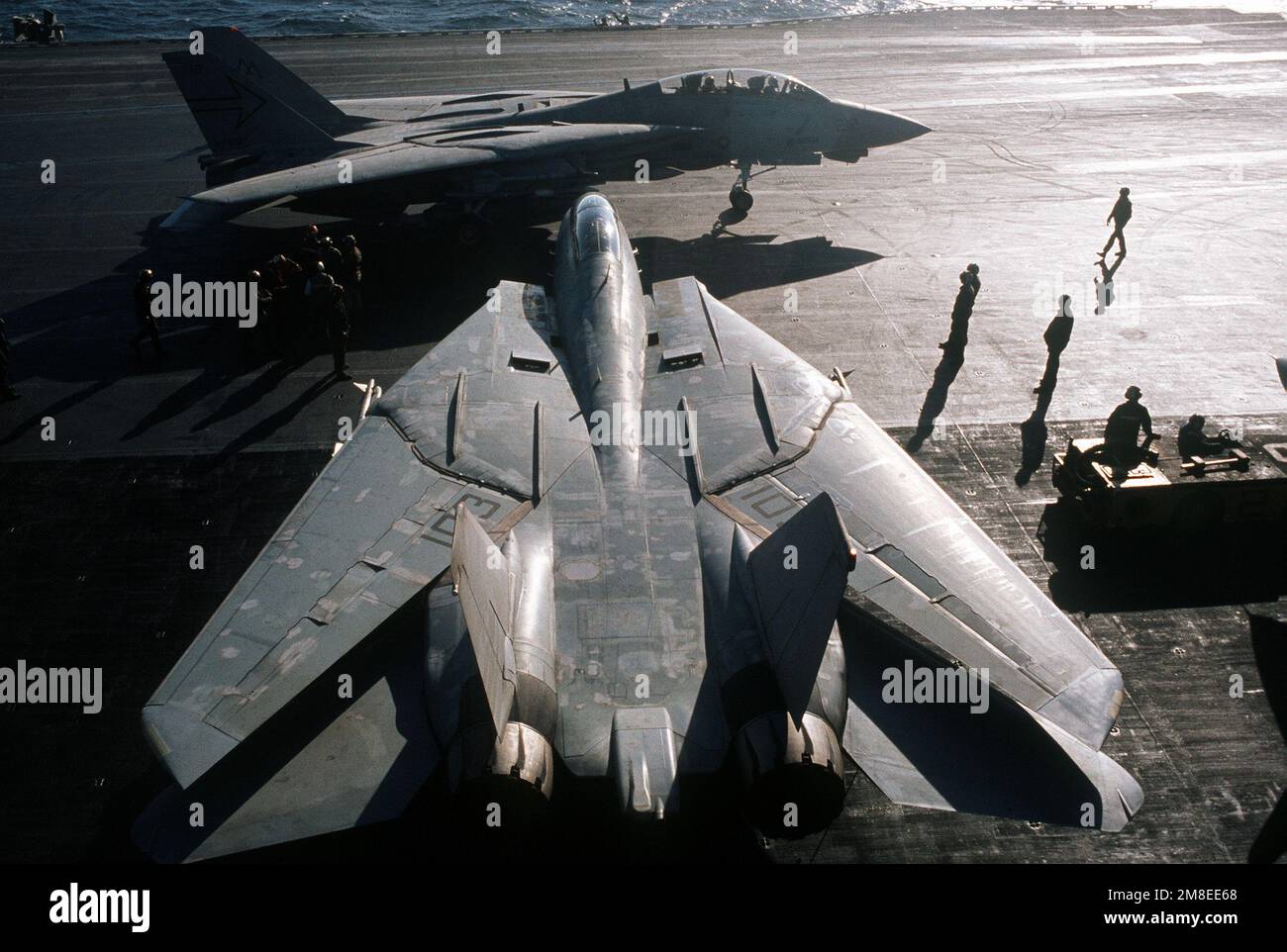A Fighter Squadron 103 (VF-103) F-14A Tomcat aircraft taxis past a parked Fighter Squadron 74 ...