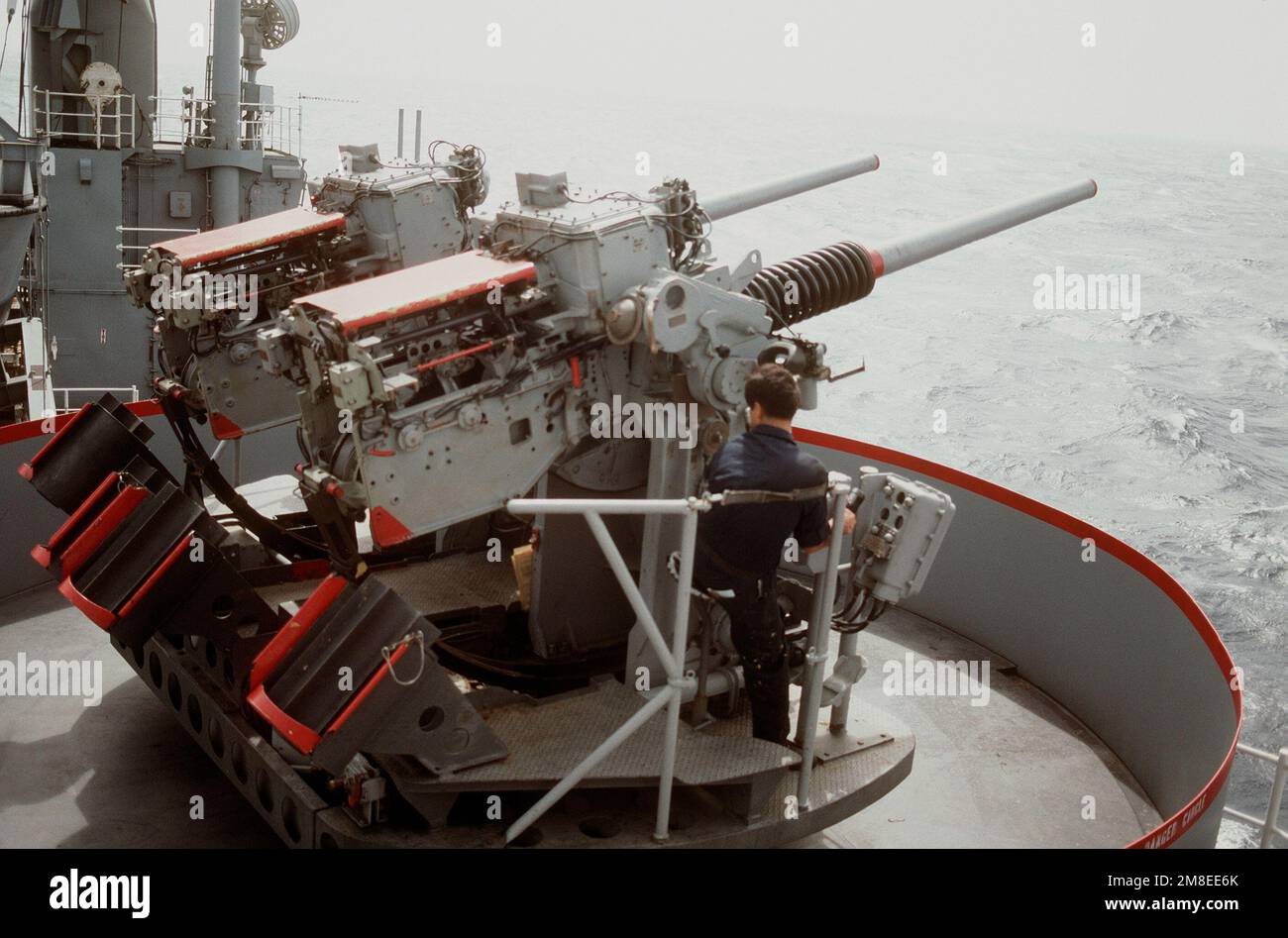 A gunner's mate inspects a Mark 33 3-inch/50-caliber gun aboard the ...