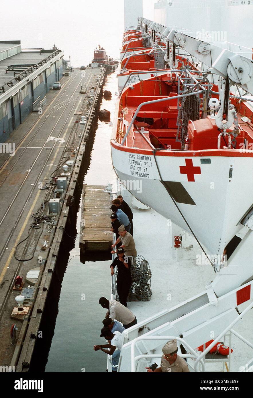Medical personnel stand beneath lifeboats aboard the hospital ship USNS ...