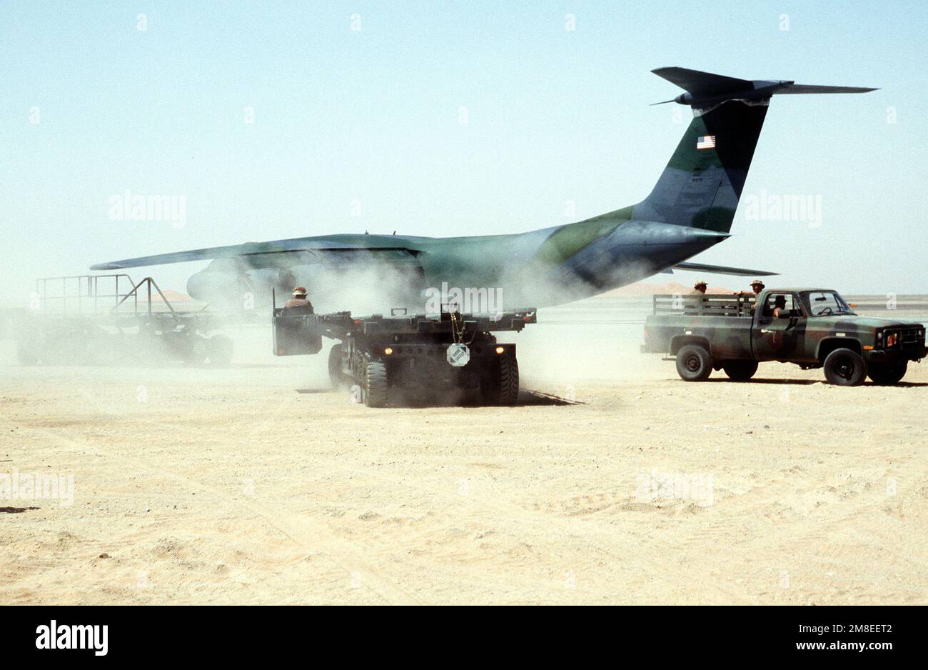 A K-loader moves along the sand near a Military Airlift Command C-141B ...
