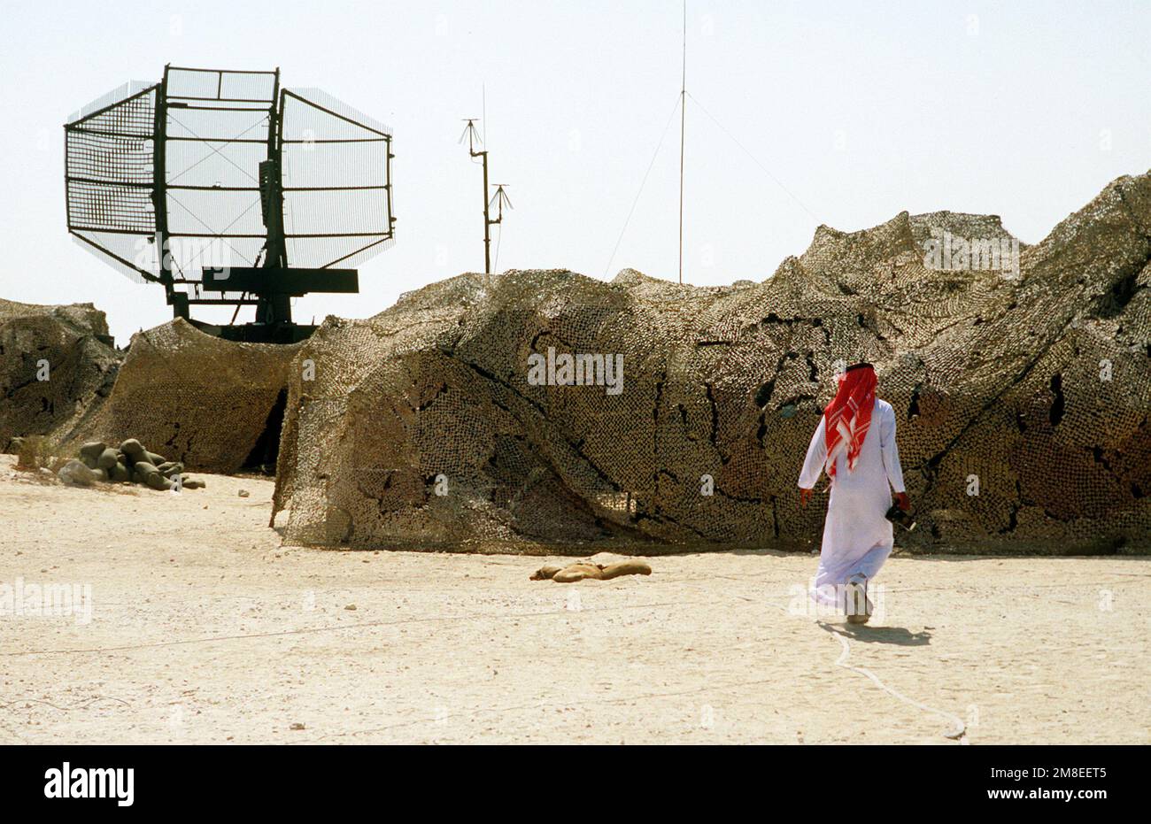 An Arab walks toward camouflaged equipment and AN/TPS-43 search radar ...