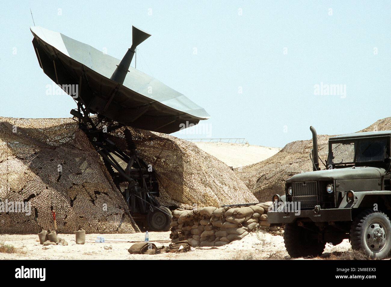 An M-54 5-ton cargo truck sits parked near an antenna at a ...