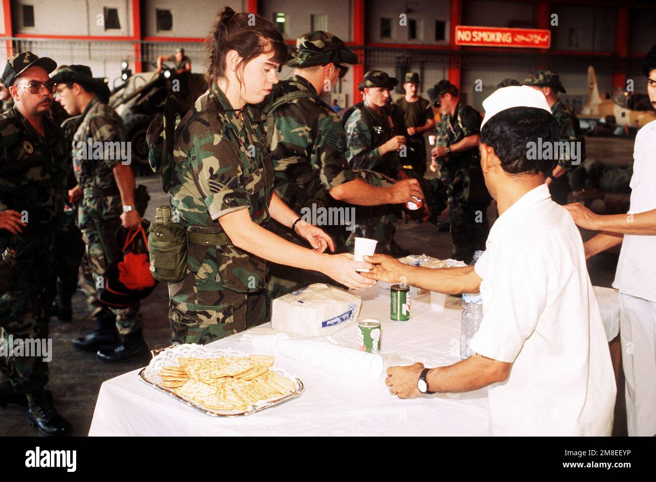 An airman gets a cold drink as she waits to go through processing after ...