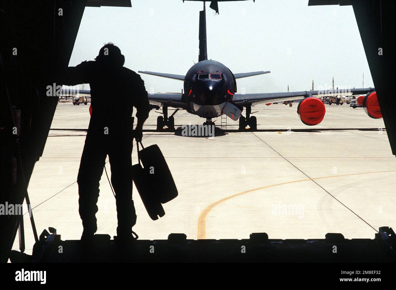 The crew chief of a C-130 Hercules aircraft carries a pair of wheel ...