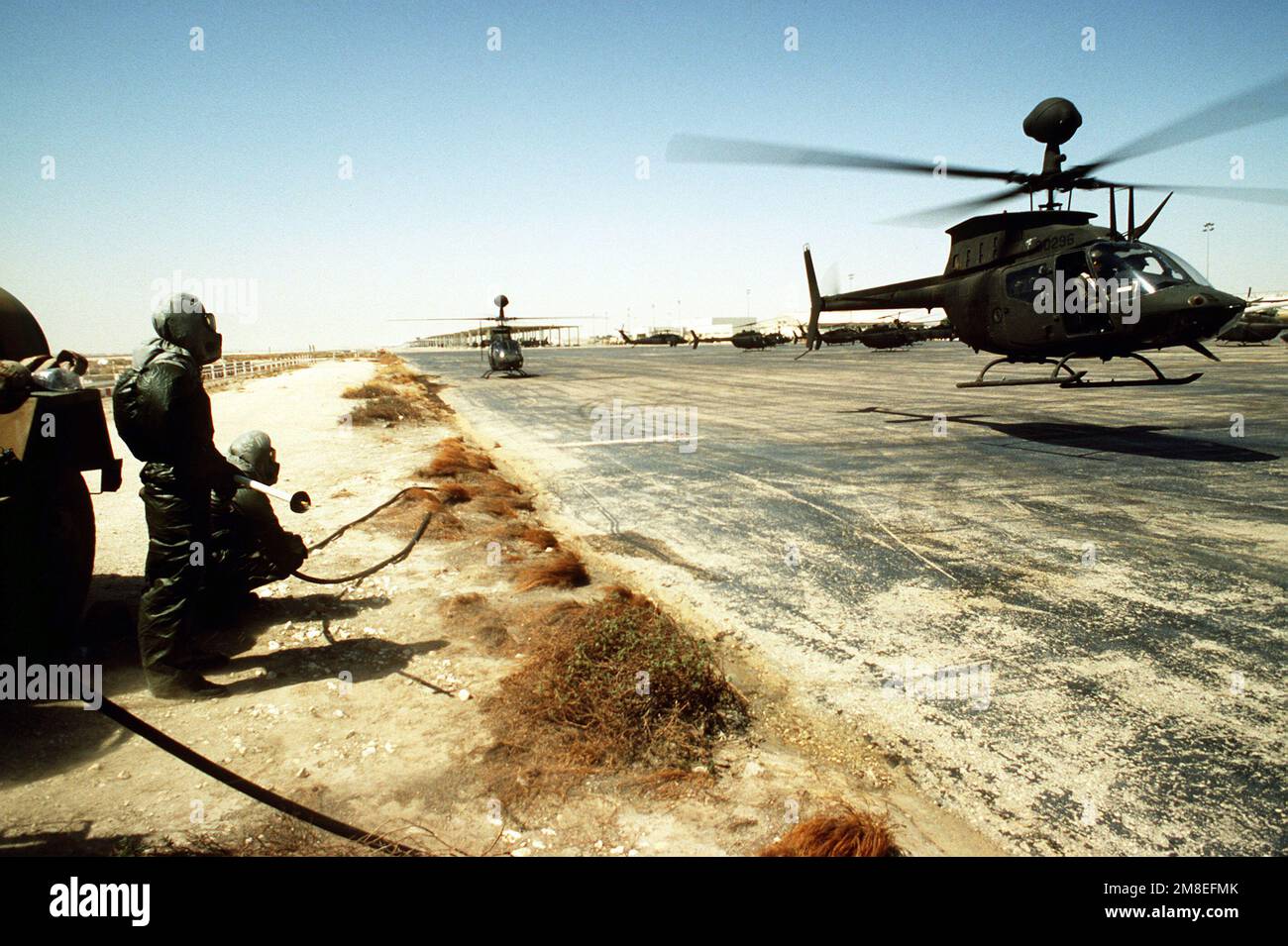 Military personnel in nuclear-biological-chemical warfare gear watch as ...