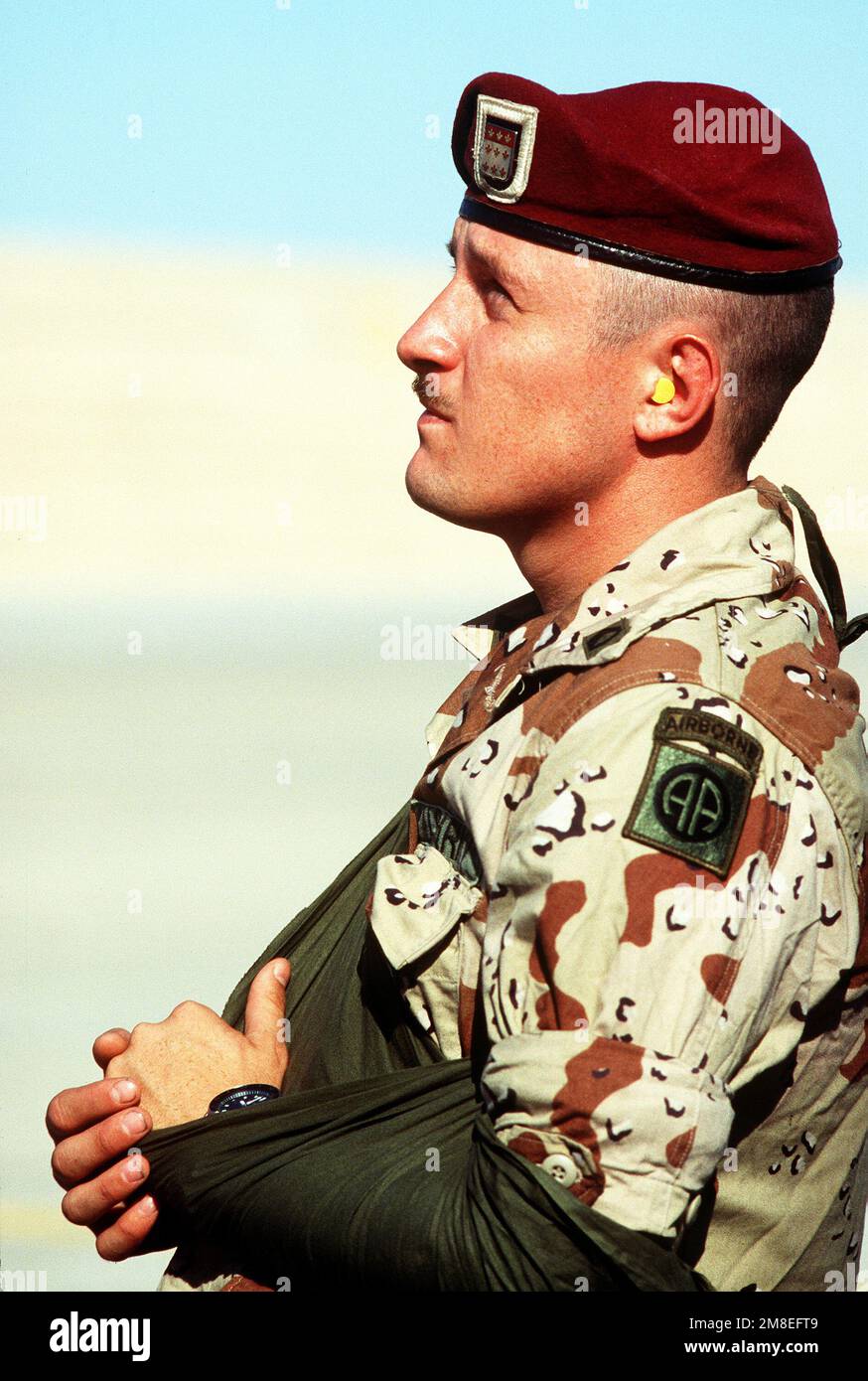 A member of the 82nd Airborne Division, his arm in a sling, waits for ...