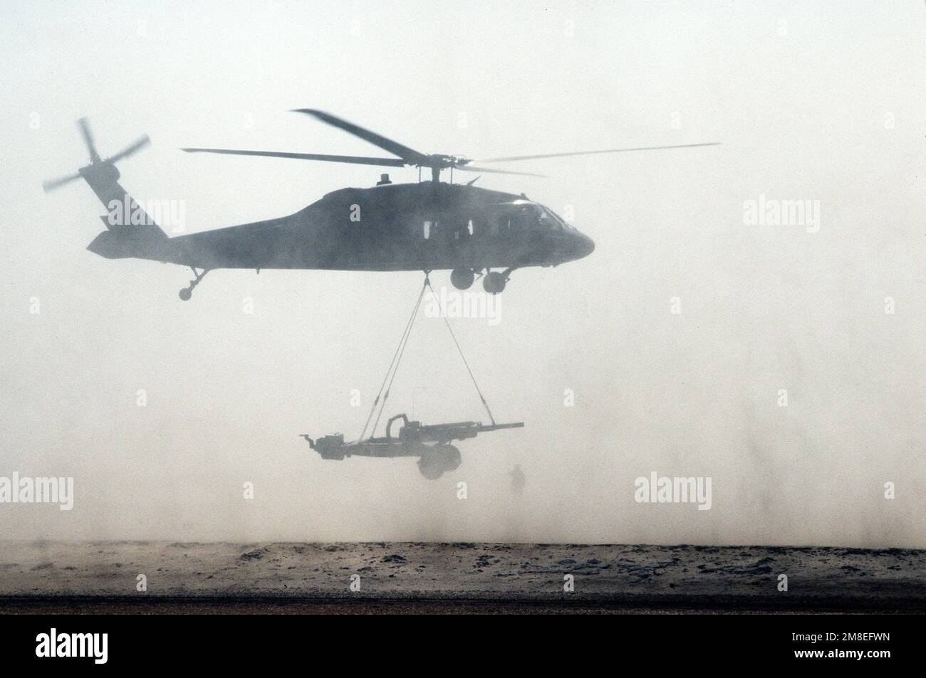 A UH-60 Black Hawk (Blackhawk) helicopter lifts a M-102 105mm howitzer ...