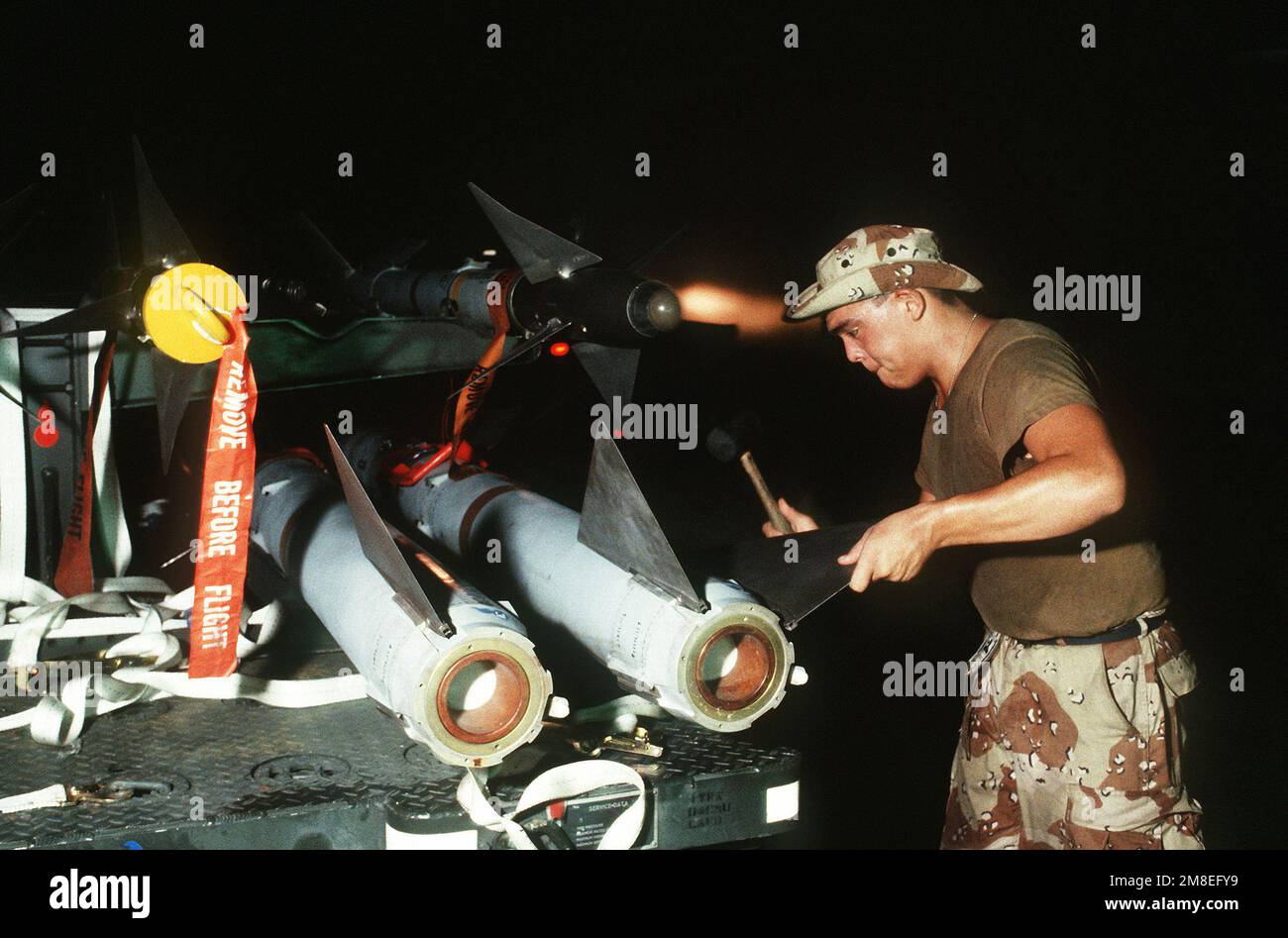 A munitions specialist attaches a tail fin on an AIM-7 Sparrow missile ...