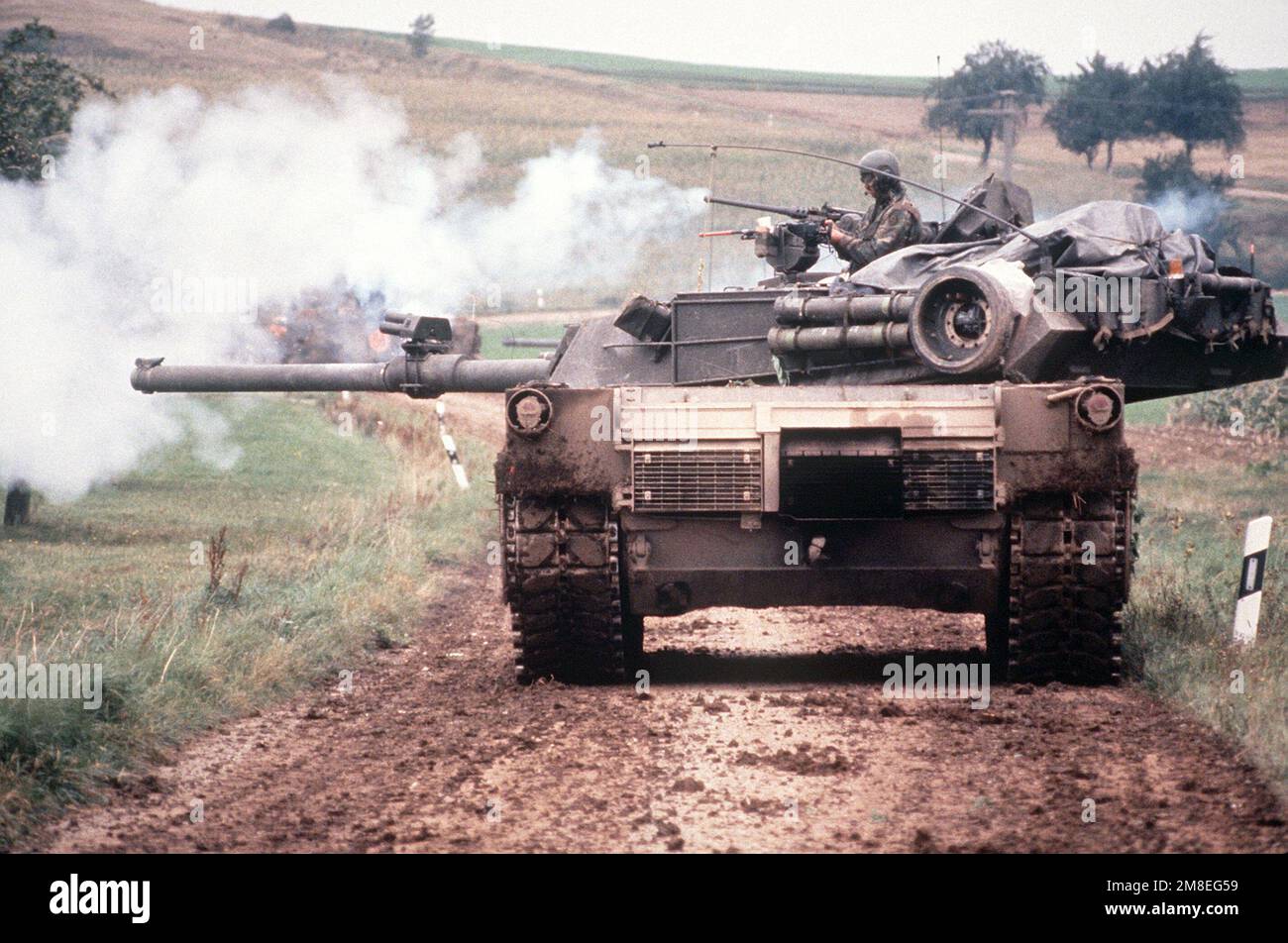 A machine gunner fires at a target from an M-1 Abrams main battle tank ...
