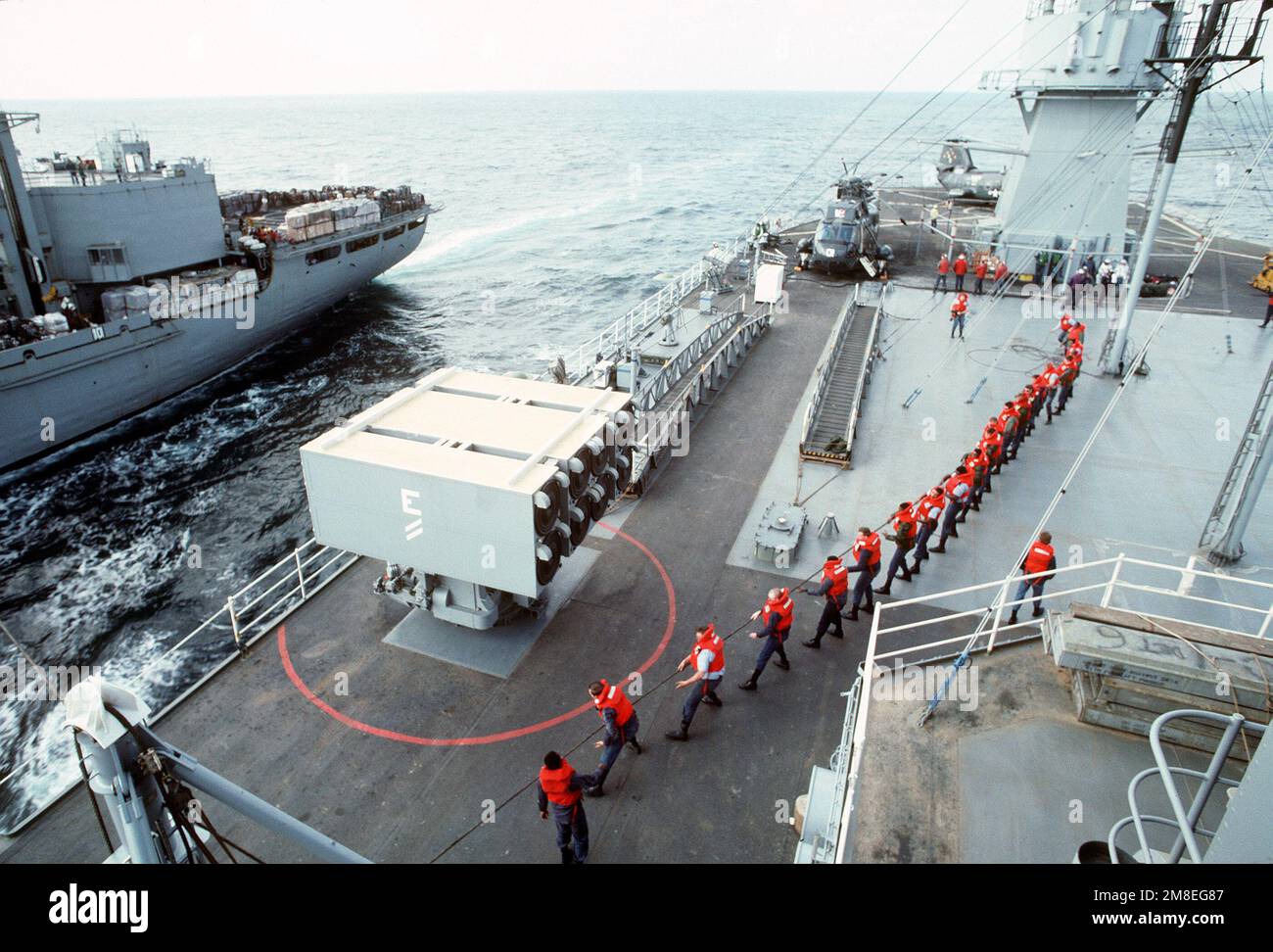 Crewmen aboard the amphibious command ship USS BLUE RIDGE (LCC-19) haul ...