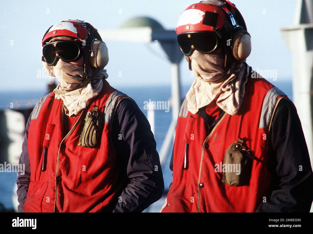 Two flight deck crewmen watch as a vertical replenishment is conducted ...
