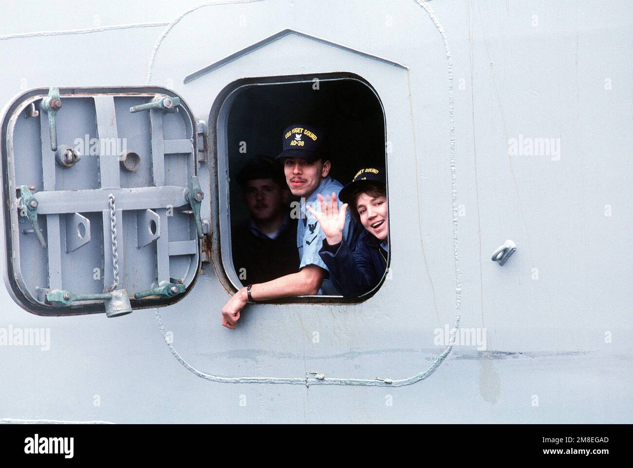 Crew members aboard the destroyer tender USS PUGET SOUND (AD-38) wave ...