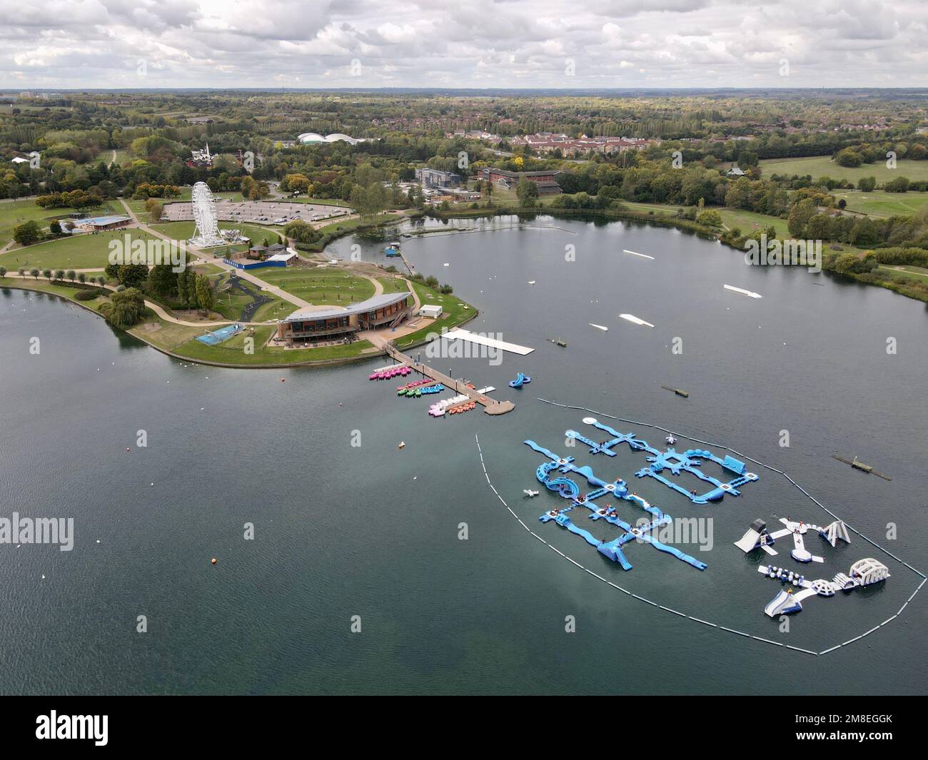 An aerial view of the coast of the Willen Lake in England with a tree ...