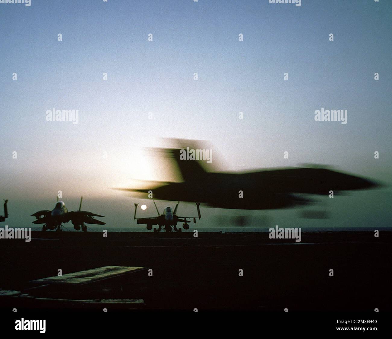 An F/A-18C Hornet aircraft speeds over the ramp as it comes in for a ...
