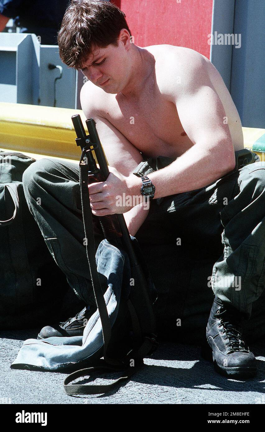 A member of Sea-Air-Land (SEAL) Team 8 wipes down his 12-gauge shotgun ...