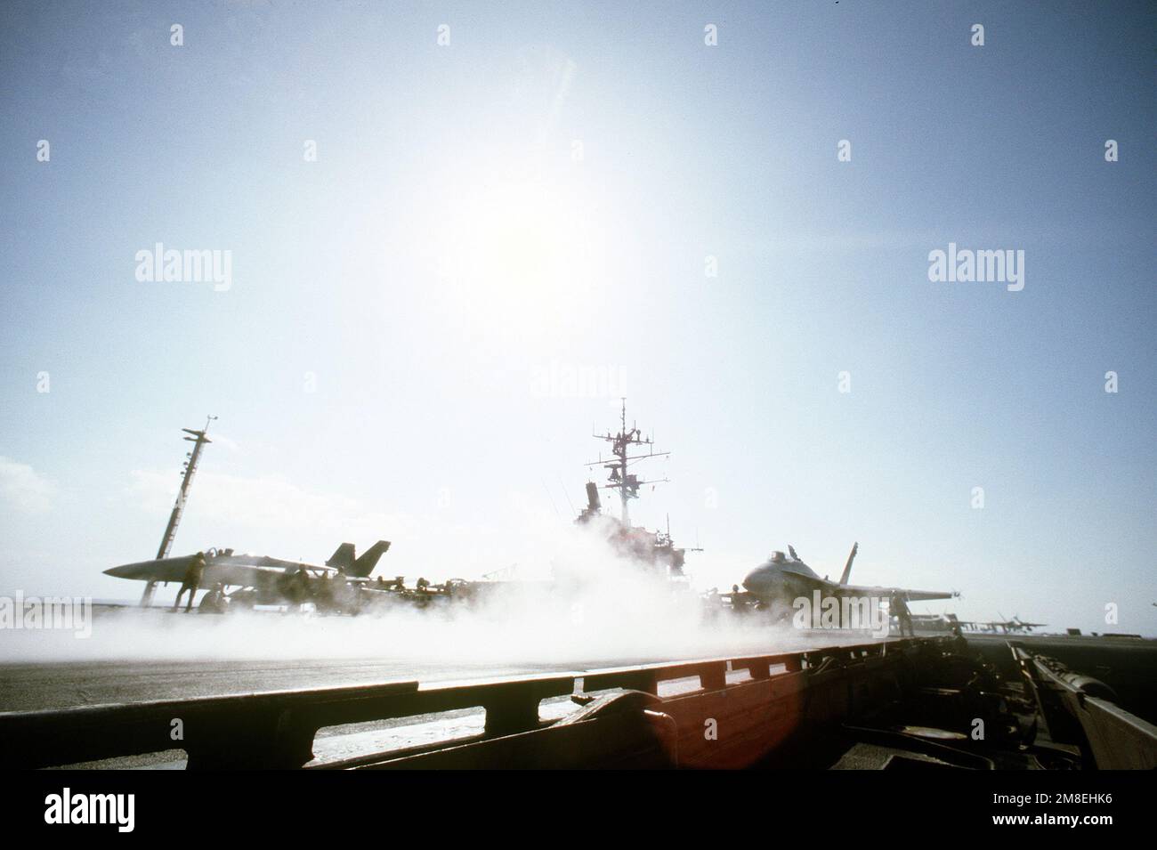 Steam rises from the catapult tracks as two F/A-18C Hornet aircraft are ...