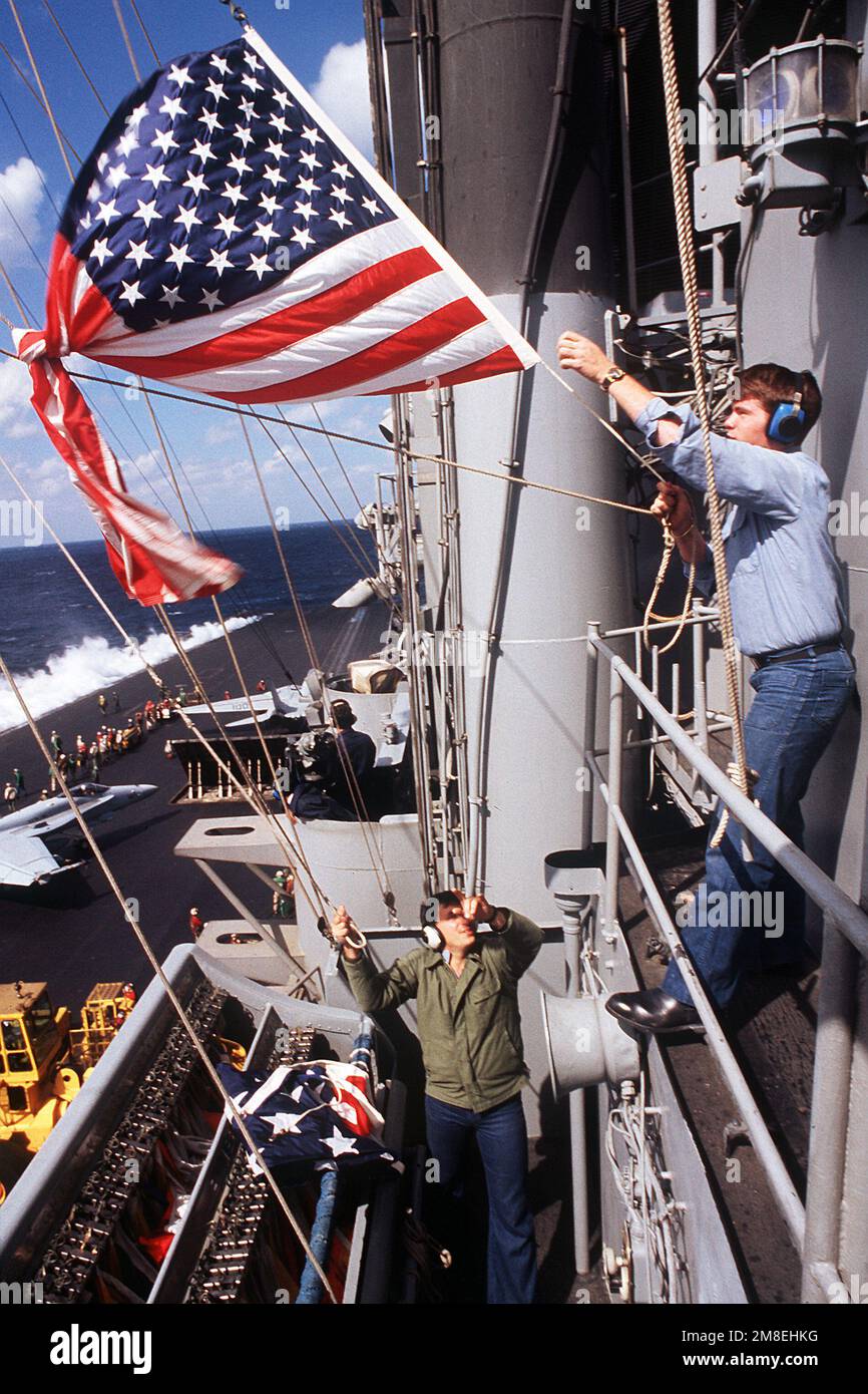 A signalman aboard the aircraft carrier USS SARATOGA (CV-60) hauls down ...