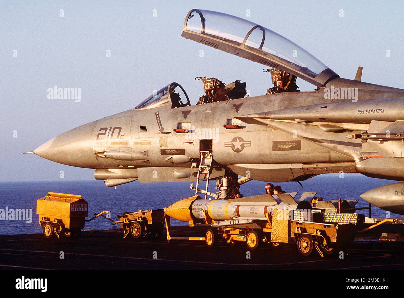 An AIM-54C Phoenix missile and two chaff and flare dispensers sit on skids beside a Fighter ...