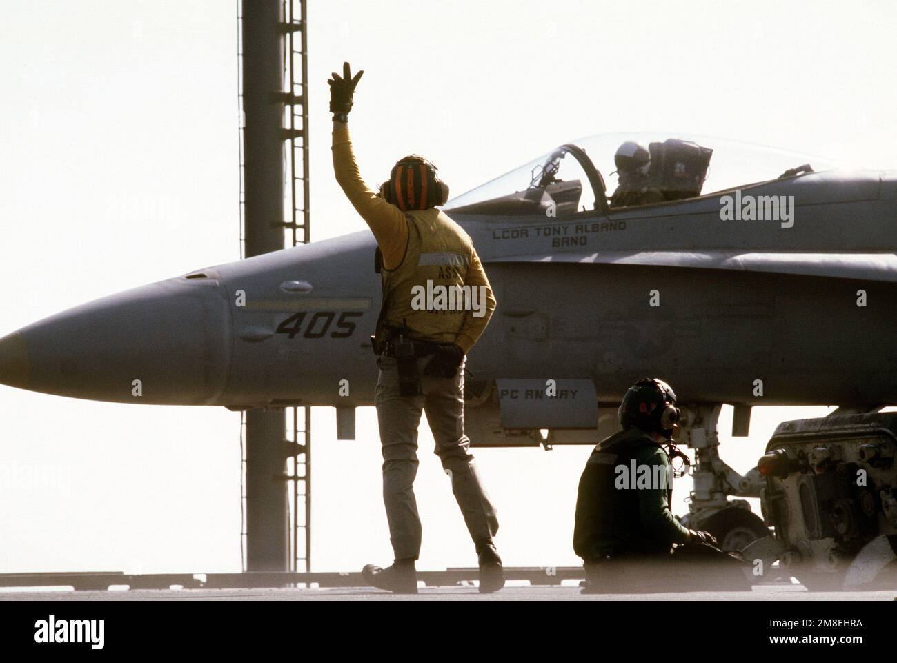 An assistant catapult/arresting gear officer signals to the pilot of a ...