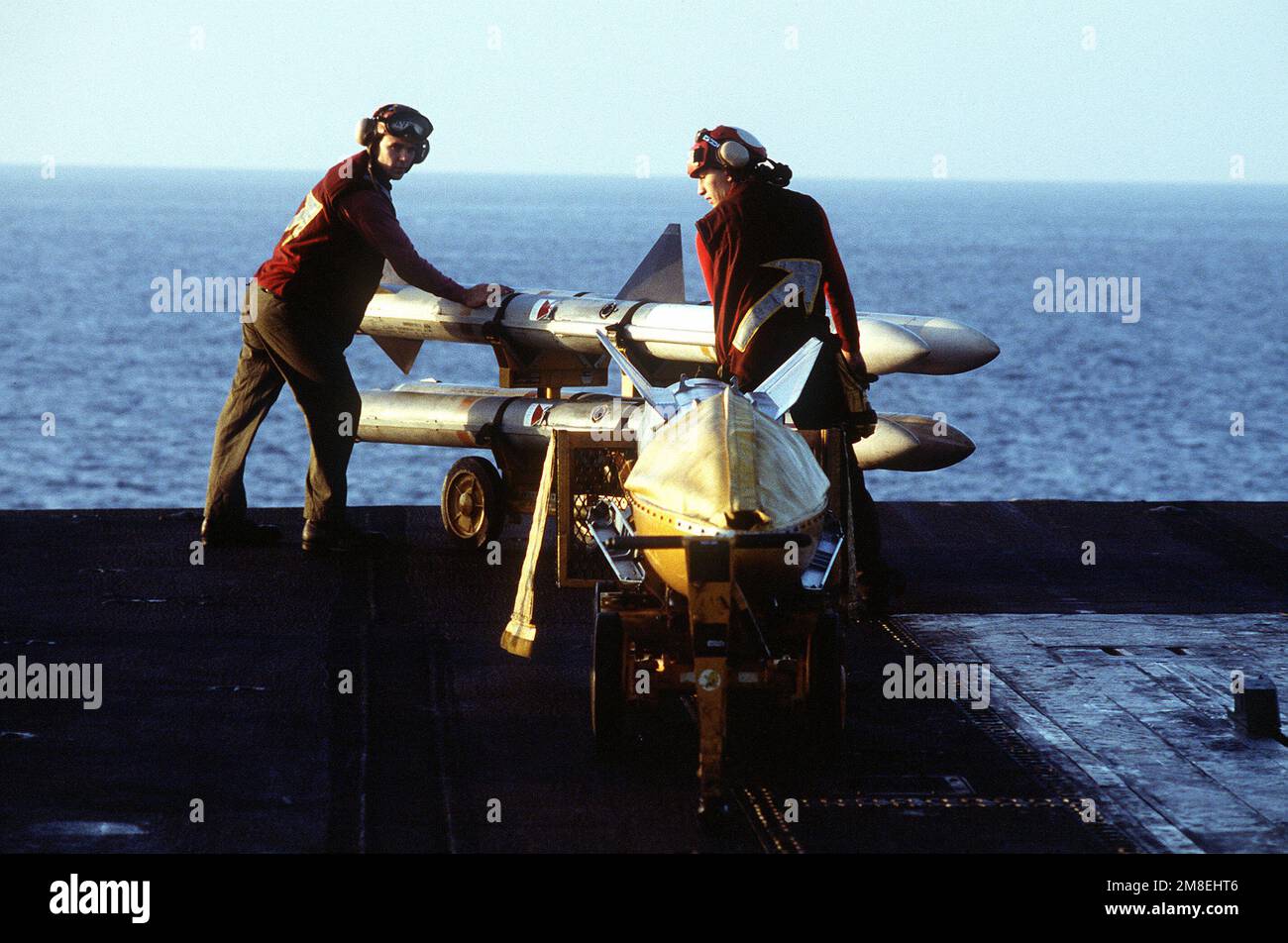 Two aviation ordnancemen from Fighter Squadron 103 (VF-103) move a skid ...