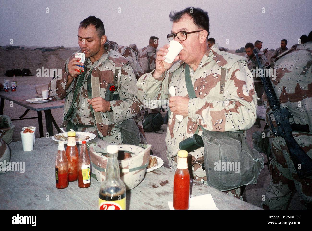 Marine Corps and Navy personnel stand at field tables to eat breakfast ...