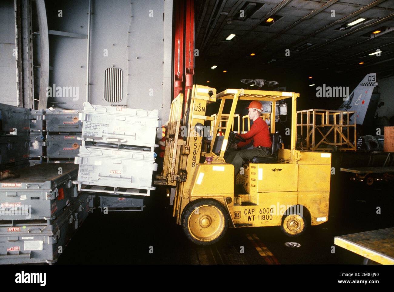 An aviation ordnancemen uses a forklift to pick up two crates of Mark ...