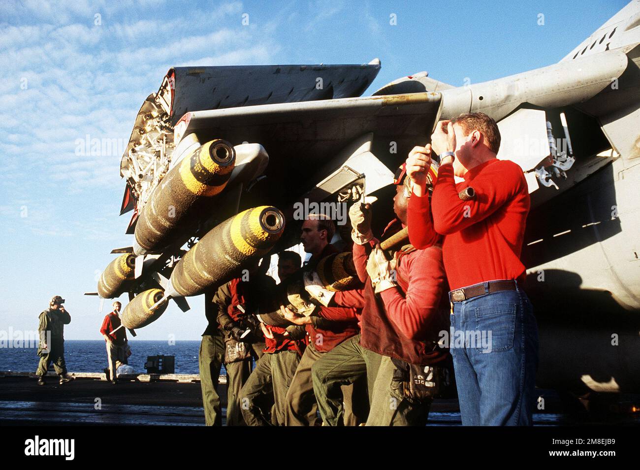 Aviation ordnancemen from Attack Squadron 75 (VA-75) hoist another Mark ...