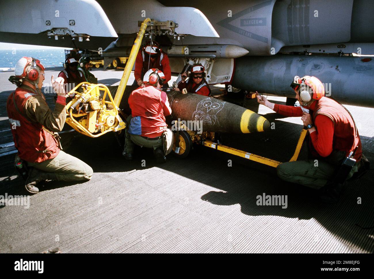 An ordnance crew member uses an HLU-196 bomb hoist to mount a Mark 84 ...