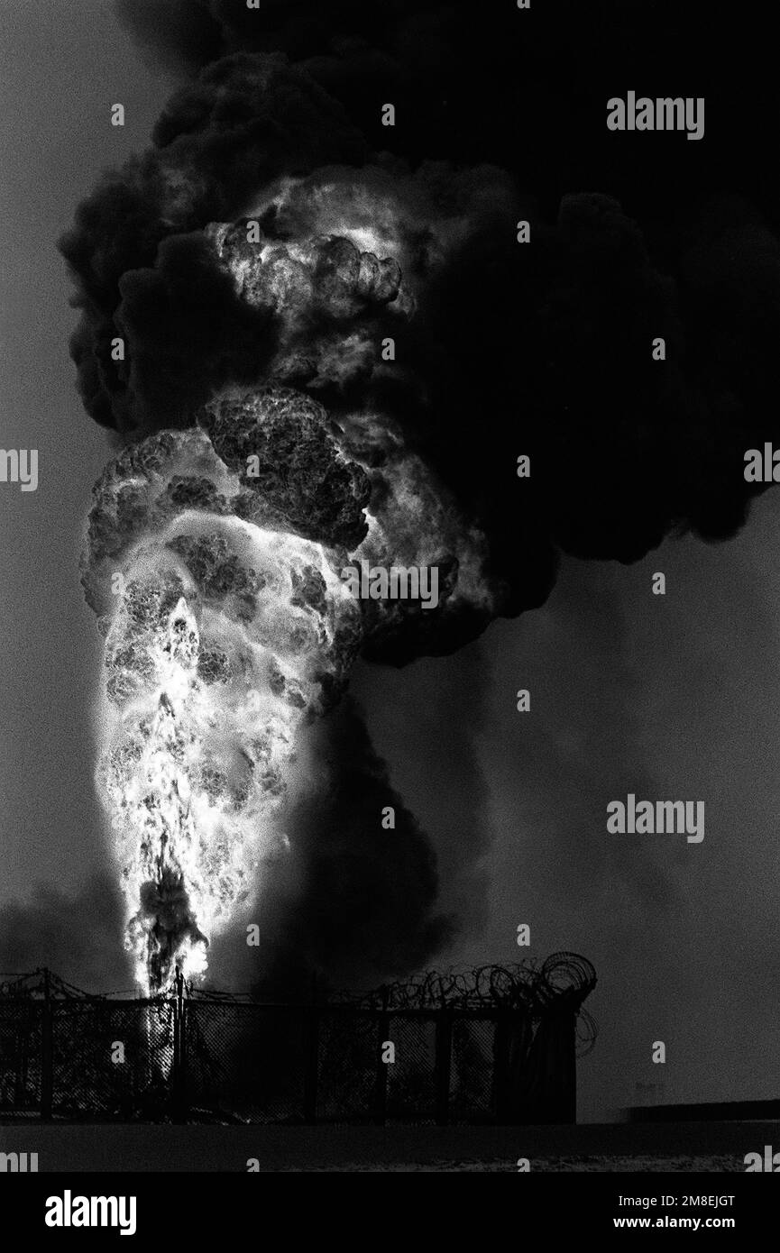A burning oil well spews flame and smoke into the air after it was set ...
