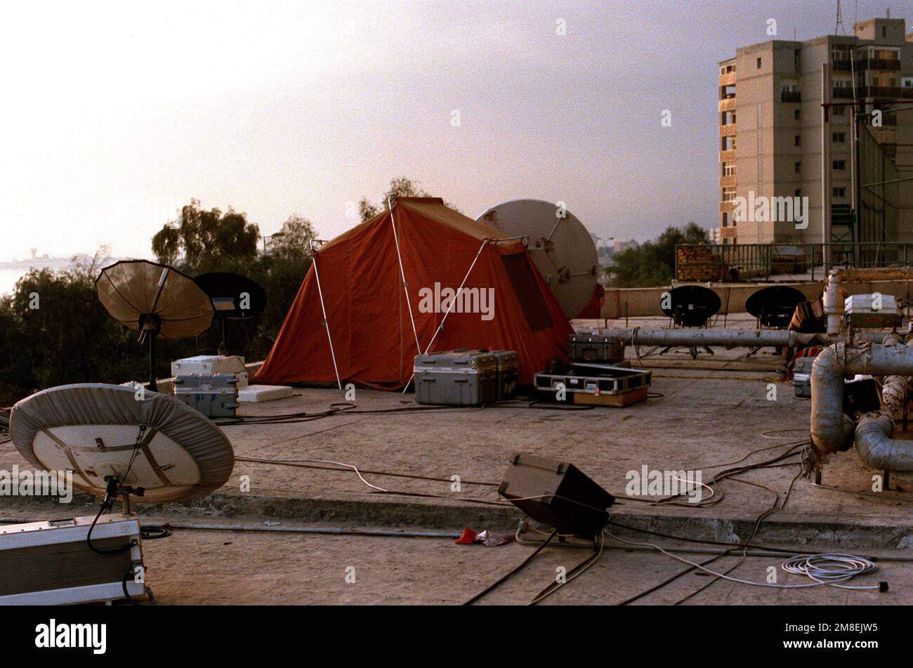 Several satellite communications antennas surround a tent on the roof ...