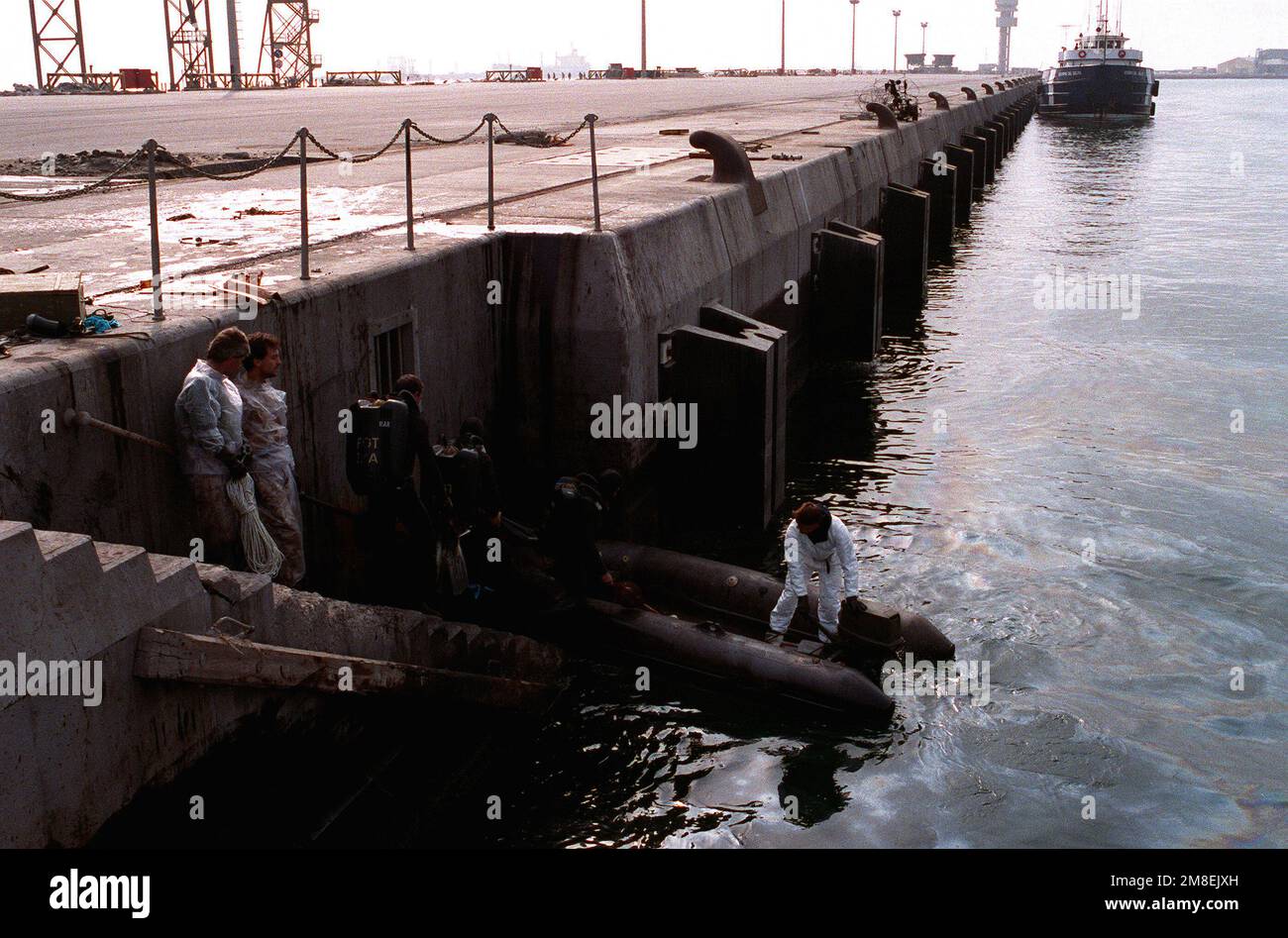 Three explosive ordnance disposal (EOD) divers climb aboard an ...