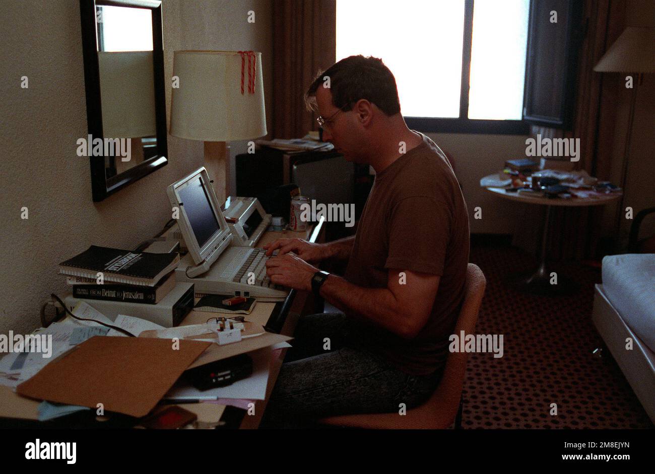 A Navy journalist works on a story in his hotel room following ...