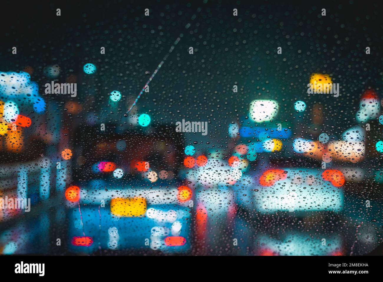 Raindrops on car windshield during night driving on a rainy evening ...