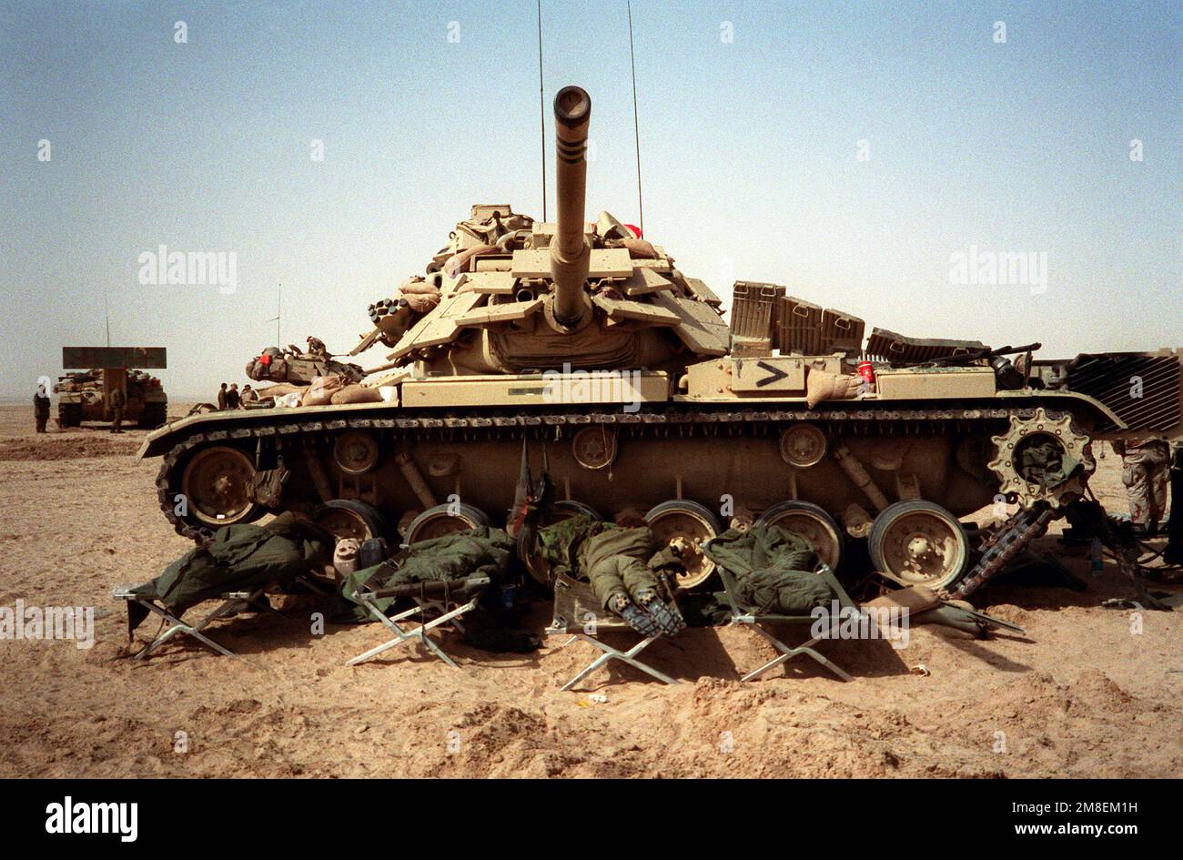 A Marine naps in his cot as other Marines work on the power pack from ...