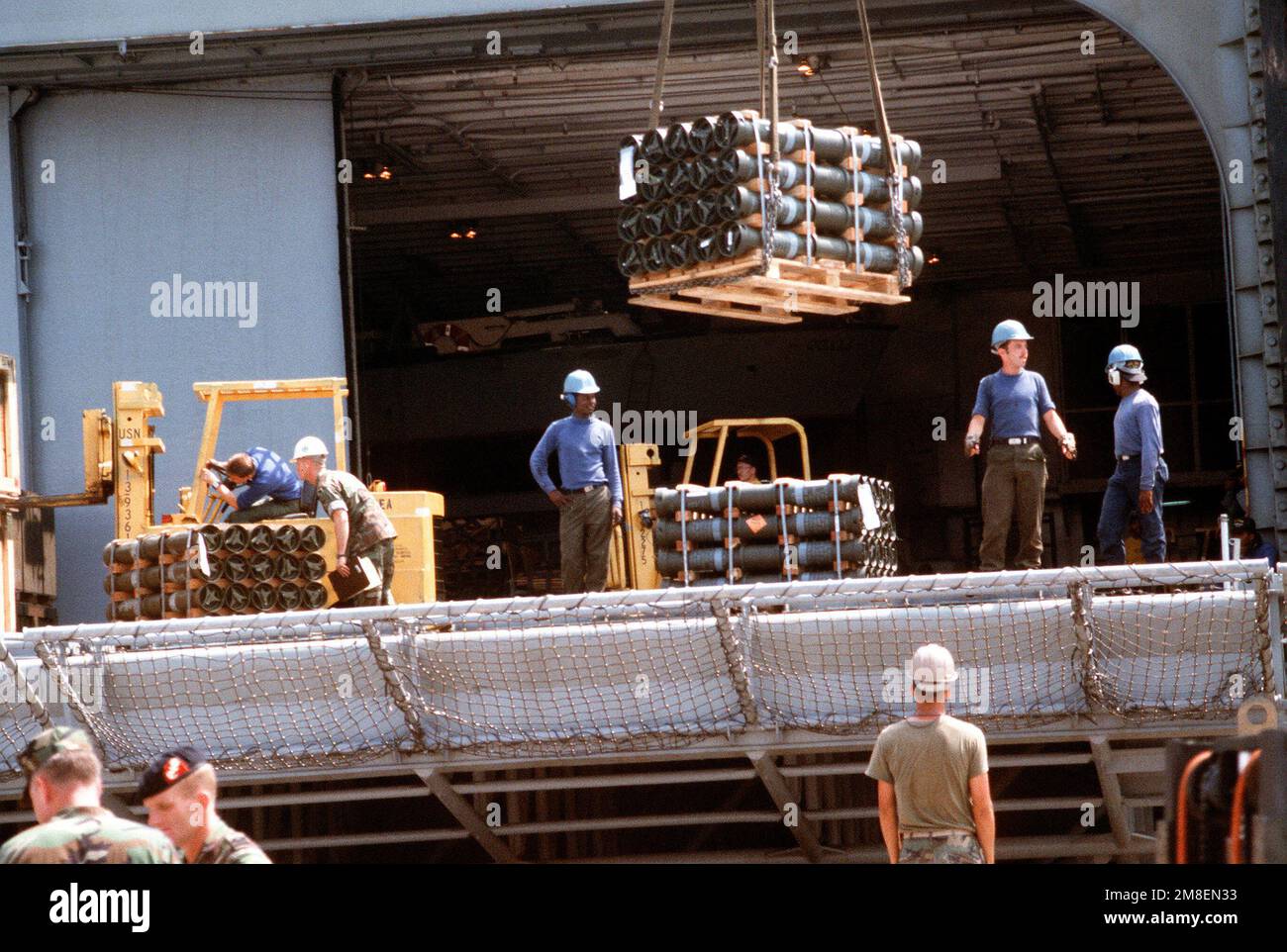 Pallets of ordnance are loaded aboard the amphibious assault ship USS ...