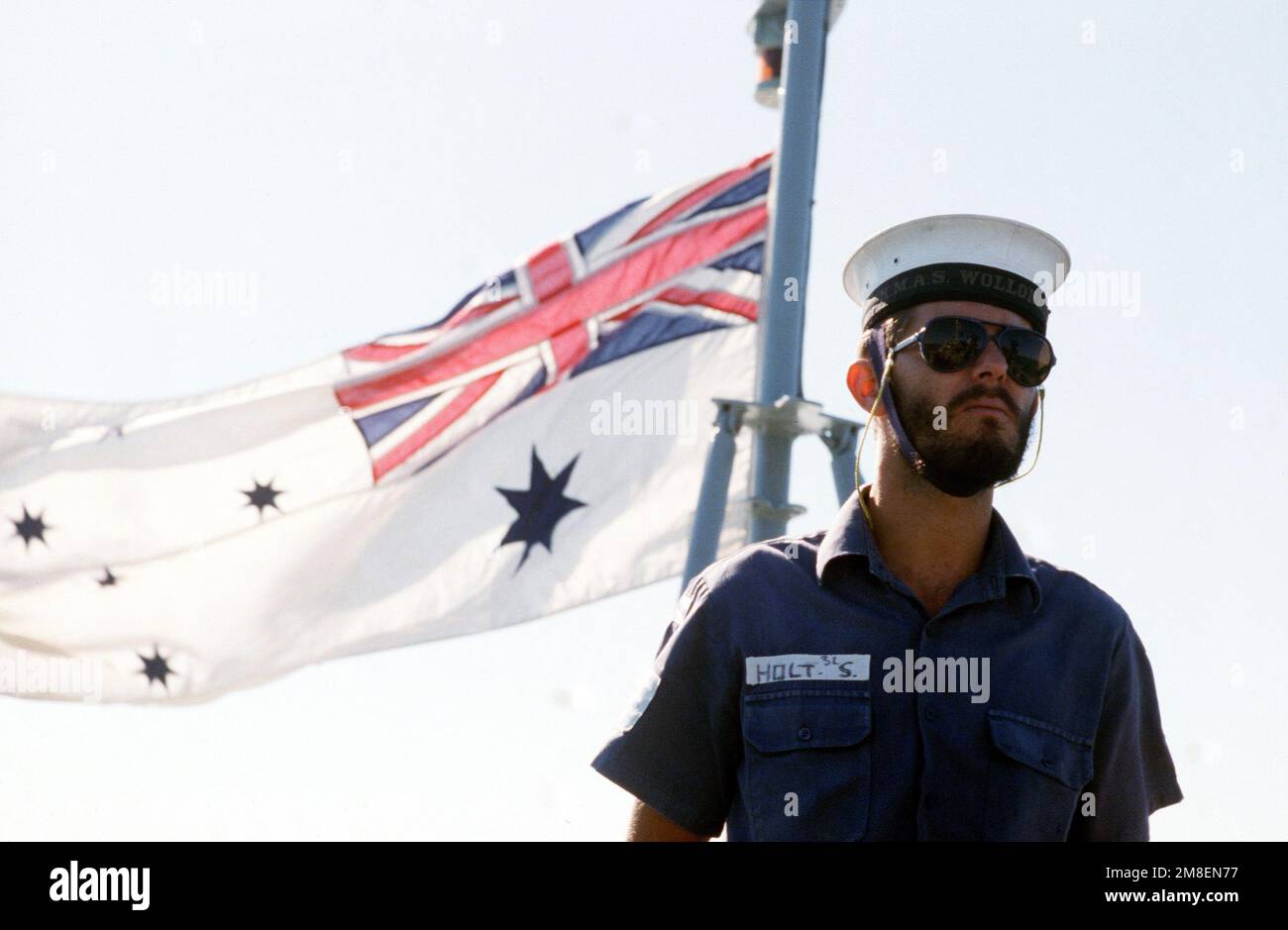 An Australian sailor stands beneath his country's flag on the large ...